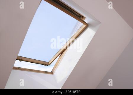 Skylight roof window on slanted ceiling in attic room, low angle view ...