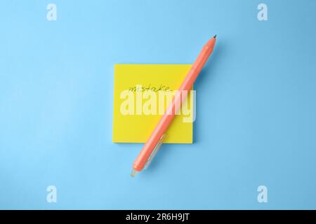 Paper notes with word Mistake and erasable pen on light blue background ...