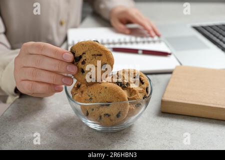 Office worker taking chocolate chip cookie from jar at workplace ...