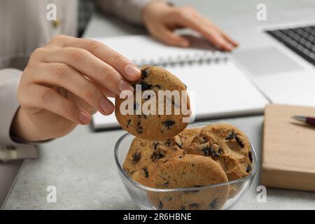 Office worker taking chocolate chip cookie from jar at workplace ...
