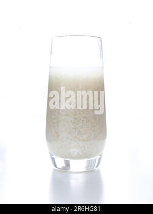 A crystal clear glass filled to the brim with white rice submerged in ...