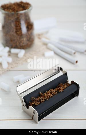Roller with tobacco on white wooden table, space for text. Making hand ...