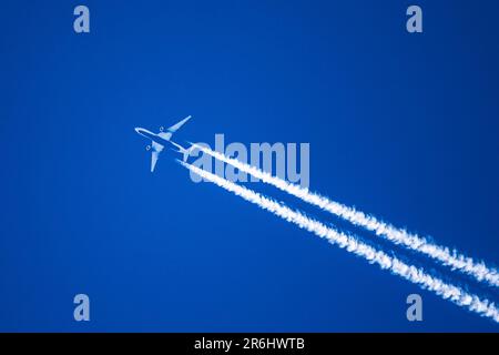 Sharp telephoto close-up of jet plane aircraft with contrails cruising ...