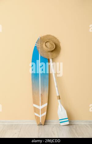 Wooden surfboard with paddle near beige wall Stock Photo - Alamy