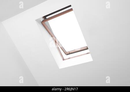 Skylight roof window and lamps on slanted ceiling in attic room, low ...