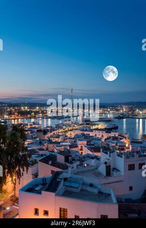Illuminated coastal town with full moon and water at night, Rising full ...