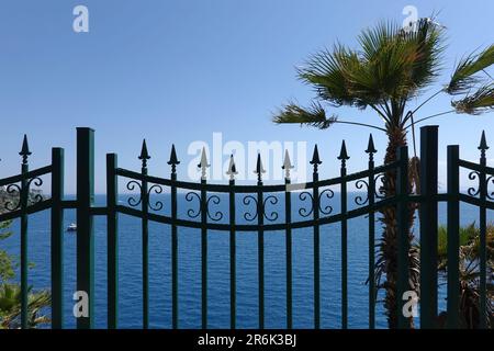 View through black sharp fencing to azure sea water surface till ...