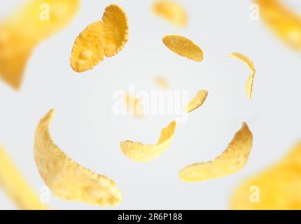 Many tasty corn flakes falling on white background Stock Photo - Alamy