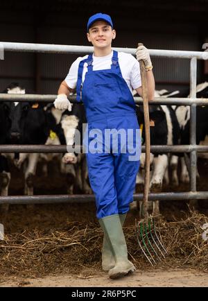 Farmer man stands with rake at cow farm Stock Photo - Alamy