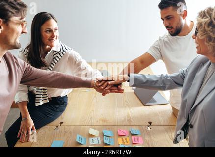 Creative business team stacking hands together in office Stock Photo ...
