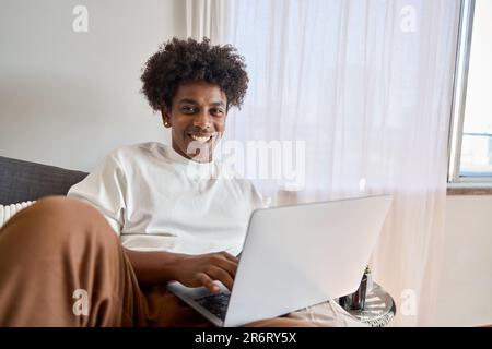 Portrait of happy young student sitting outdoors on steps with laptop ...