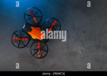 Orange quadcopter mini spy drone on a dark background with blue ...