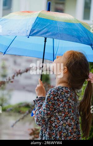 A girl under an umbrella jumping near a lake in a mountainous area in ...