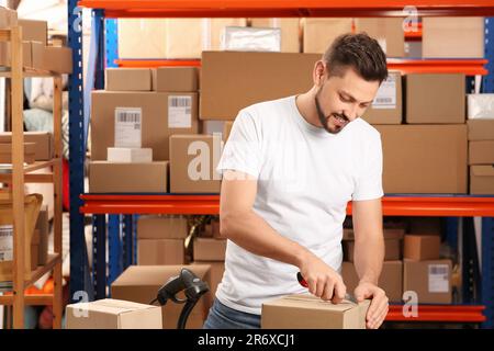 Post office worker with utility knife opening parcel indoors Stock ...