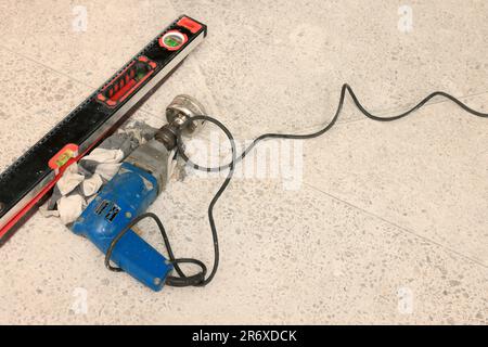 Buffing attachment drill and building level on floor, flat lay. Tiles ...