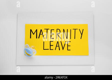 Note with words Maternity Leave, baby pacifier and paper cutout of ...