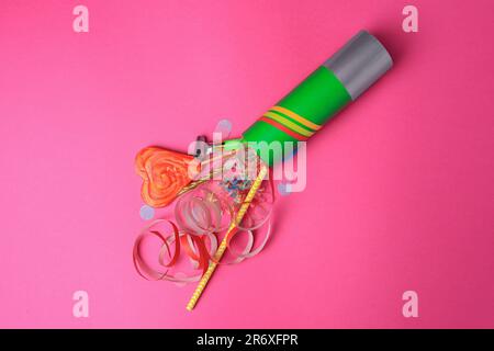 Party cracker and different festive items on bright pink background ...