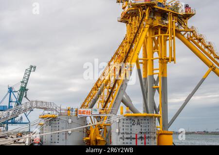 Two workers climb to the top of the first float for an offshore wind ...