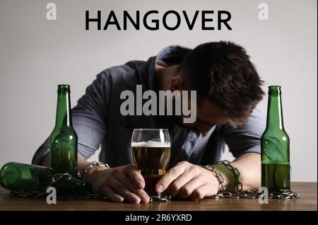 Suffering from hangover. Man chained with alcoholic drink at table ...