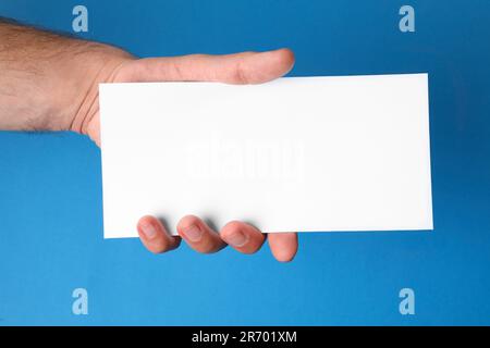 Man holding flyer on blue background, closeup. Mockup for design Stock ...