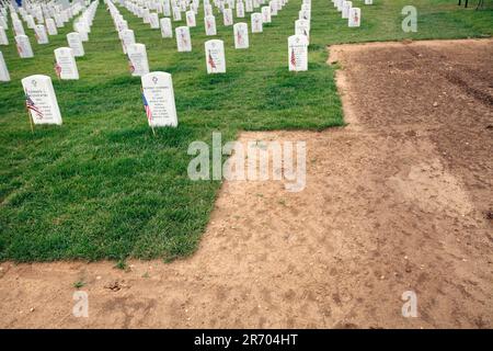 Grass and gravestones border mud from newly dug graves at Section 60 in ...