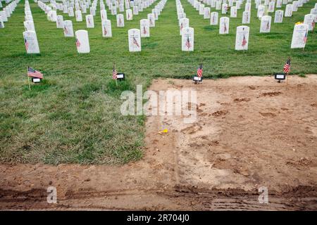 Grass and gravestones border mud from newly dug graves at Section 60 in ...