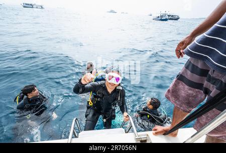 diver climbing up to a boat after finishing a dive in the Maldives ...