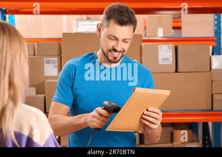 Post office worker with scanner reading parcel barcode at counter ...