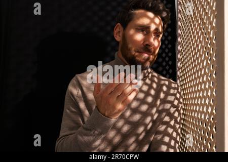 Upset man talking to priest during confession in booth, space for text ...