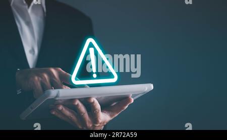 Businessman using tablet with triangle caution warning sing for ...
