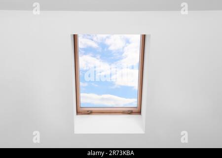 Skylight roof window and lamps on slanted ceiling in attic room, low ...