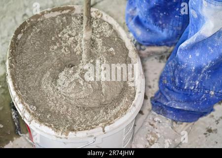 Mortar cement paste, mostly dry, mixed in bucket at house construction ...