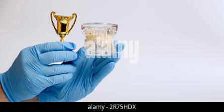 Dentist holding a trophy and a tooth model on a white Stock Photo - Alamy