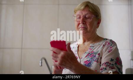 Tech-savy senior woman using phone. Elderly 80s female person holding ...