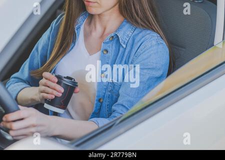 Female spilling coffee or tea on herself while driving a car. Dirty ...