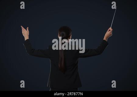 Back view of professional conductor with baton on black background ...