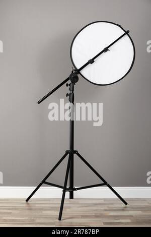 Professional light reflector near grey wall in room, space for text ...