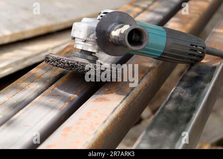 Not new electric angle grinder tool lies on a rust metal square tube ...