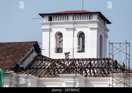 Old Goa, India - January 2023: Workers fixing the tiles on the roof ...