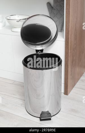 Opened metallic trash bin near table in interior of modern kitchen ...