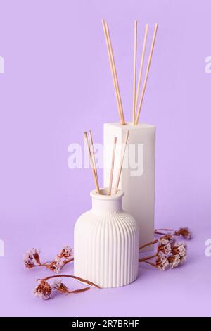 Bottles of reed diffuser and flowers on purple background Stock Photo ...