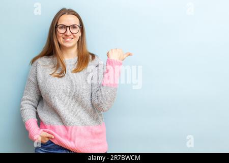 Woman pointing to the side on blue background Stock Photo - Alamy