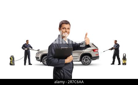 Workers in uniforms washing a SUV with a pressure washer machines ...