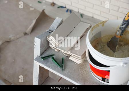 Bucket with cement, tile spacers and many white decorative bricks in ...