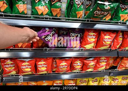 Grocery store aisle with shelves of chips and crackers, sale tags, and ...
