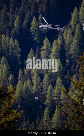 helicopter flight transport over the forest in swiss alps Stock Photo ...
