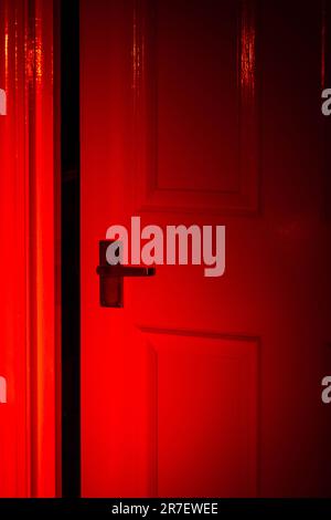 Opened door with red light shone onto it Stock Photo - Alamy