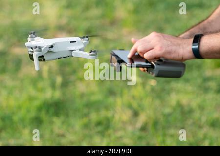 Man piloting a drone using a controller equipped with a joystick and a ...