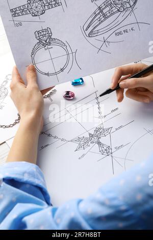 Jeweler drawing sketch of elegant necklace on paper at white wooden ...