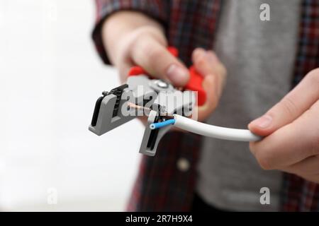 Professional electrician stripping wiring on white background, closeup ...